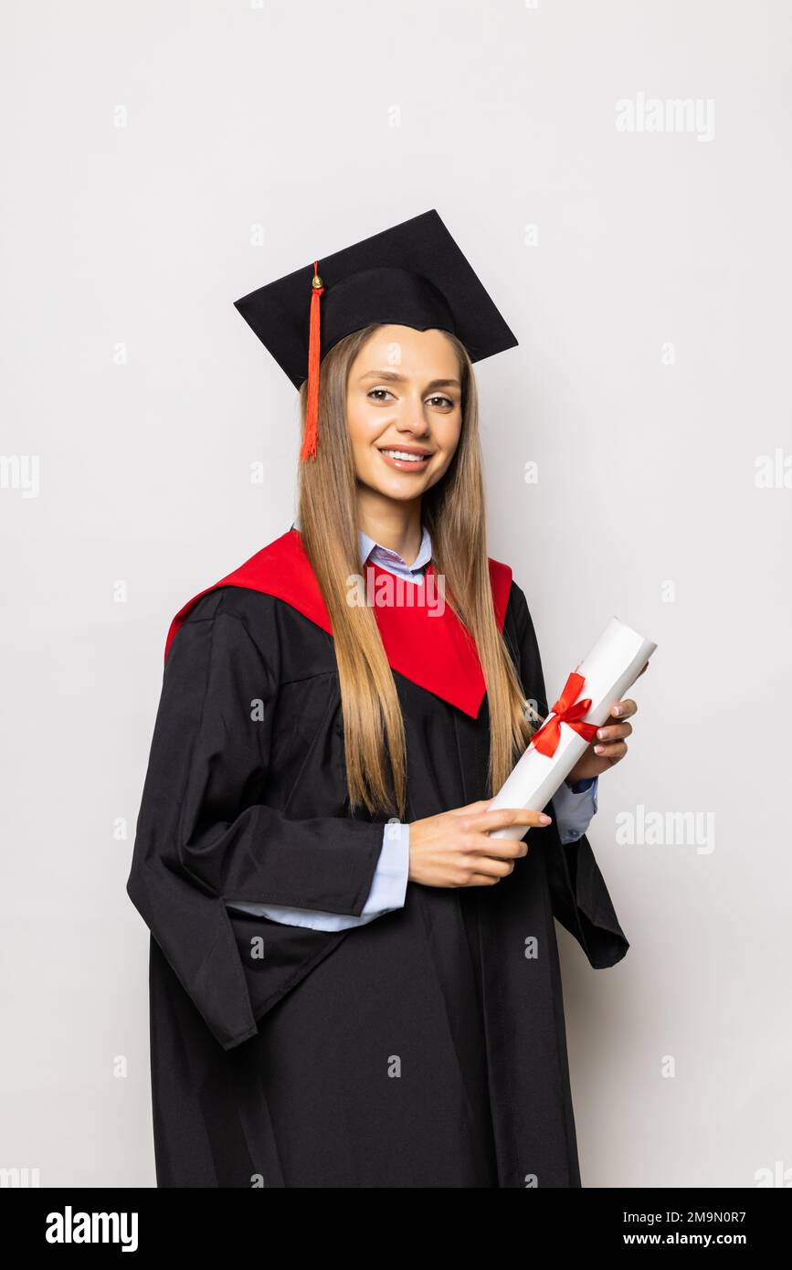 Attractive woman wearing a graduation gown and looking at the camera ...