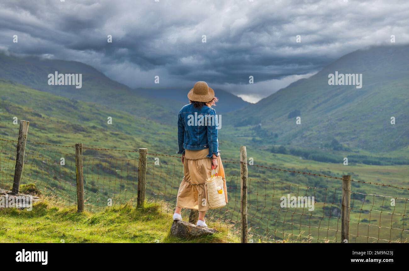 Young woman in a dress enjoys the views of Killarney National Park, the ...