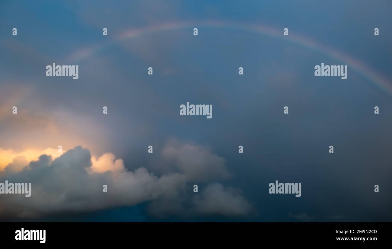 Amazing cloudy skies with colourful rainbows Stock Photo - Alamy