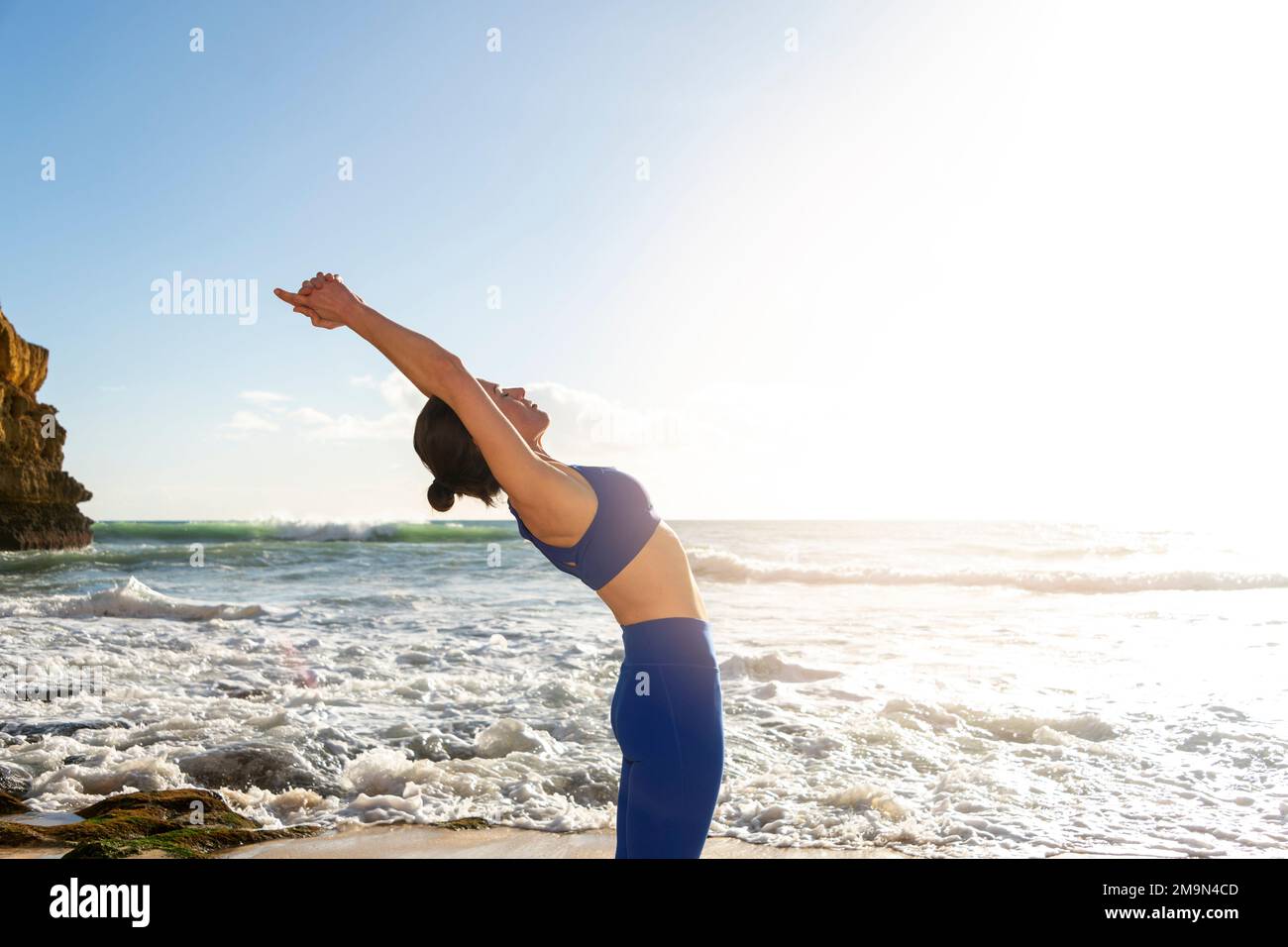female swimmer standing on the beach doing stretching exercises Stock ...