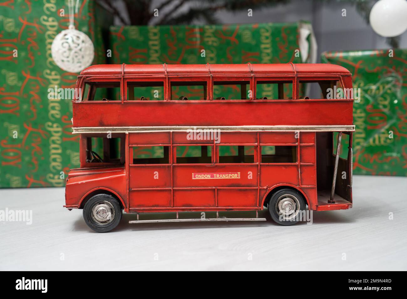 Red double-decker London bus toy on a white surface with green gift ...