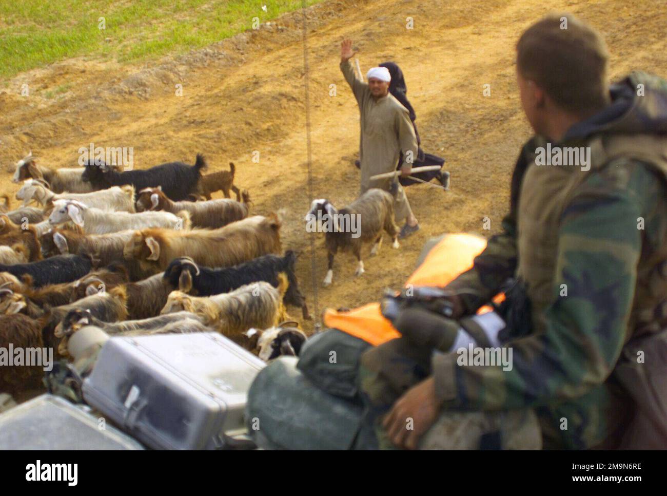 An Iraqi family waves as they shepherd their flock of goats past a US ...