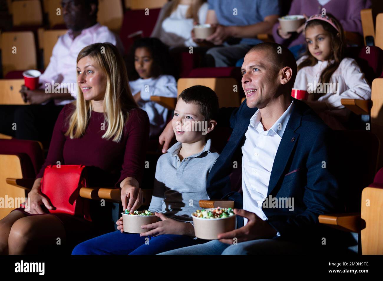 Friendly family laughing while watching funny movie in cinema Stock ...