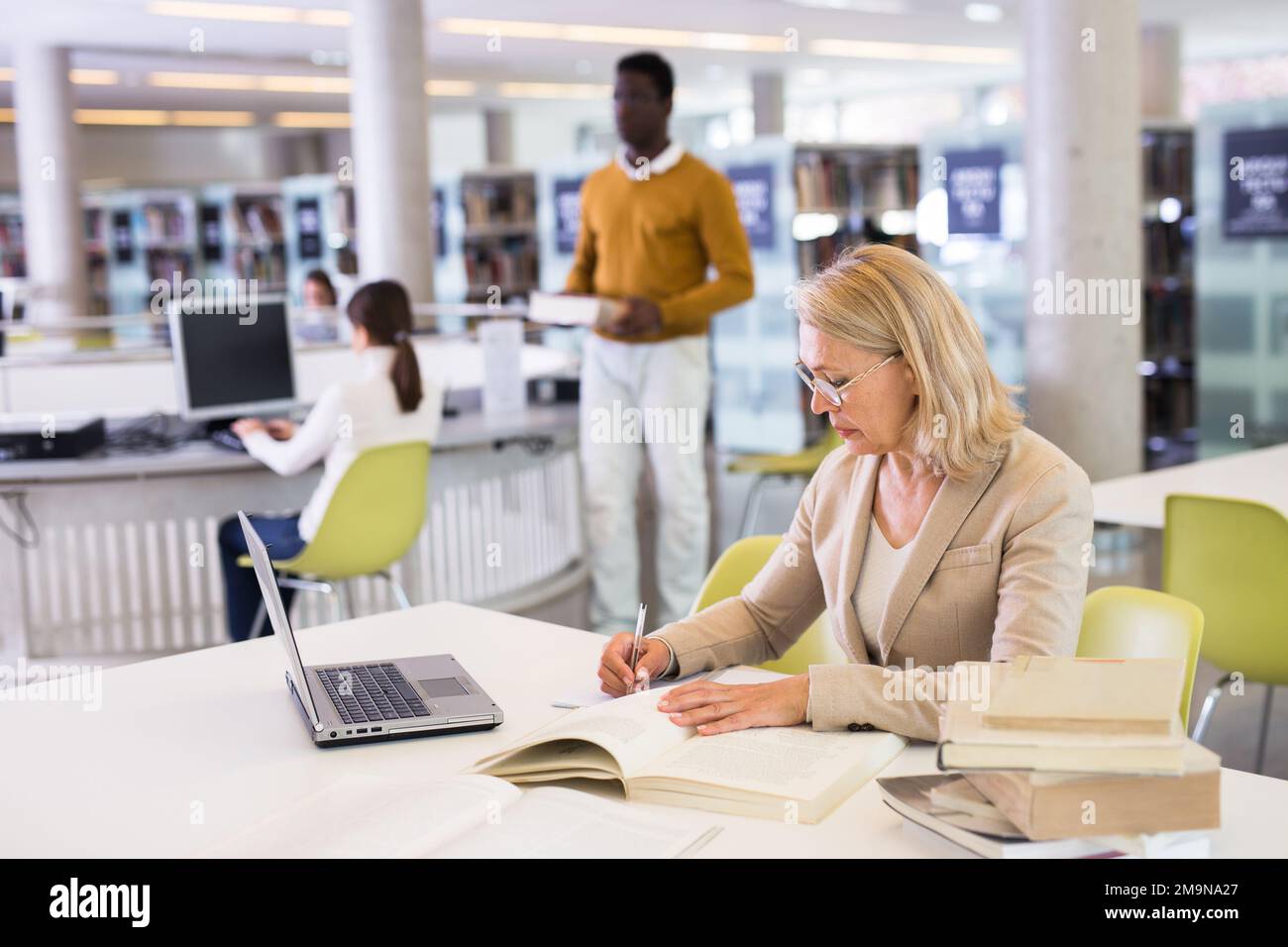 Mature teacher engaged in a public library Stock Photo - Alamy