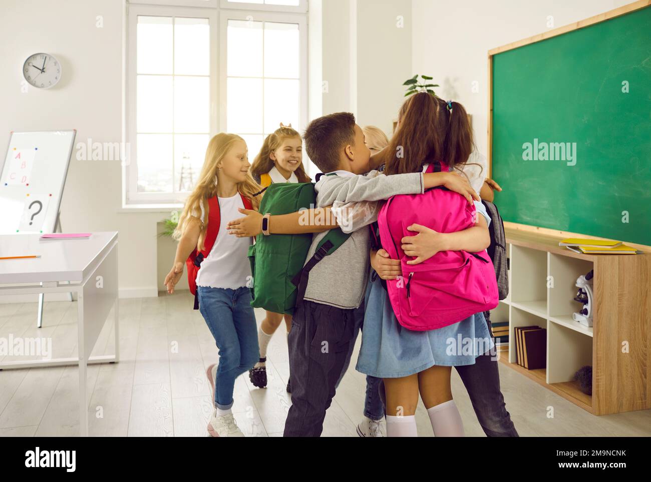 Joyful elementary school students gather in circle and hug at school ...