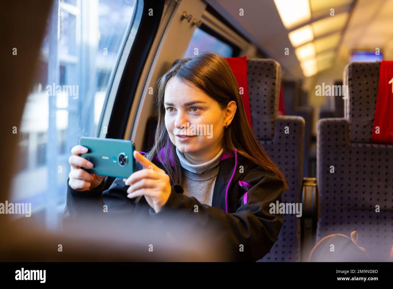 Woman taking pictures with her smartphone during train ride Stock Photo ...