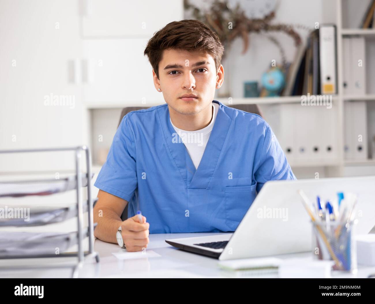 Positive man doctor therapist sitting in office at workplace and ...
