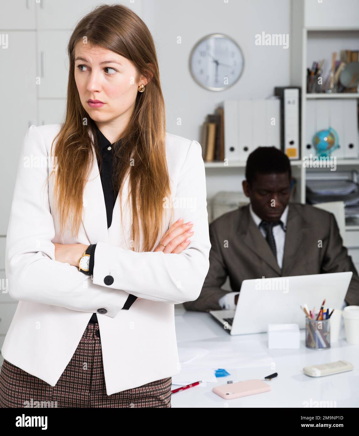 Upset woman and man colleague working with laptop on background in ...