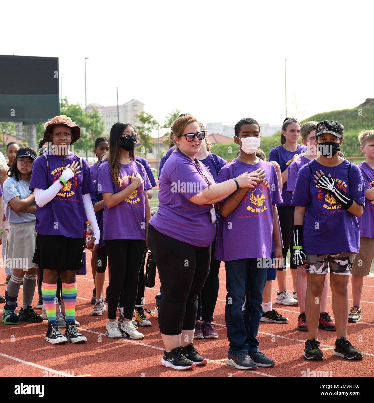 Teachers and students place their hands over their hearts during the ...