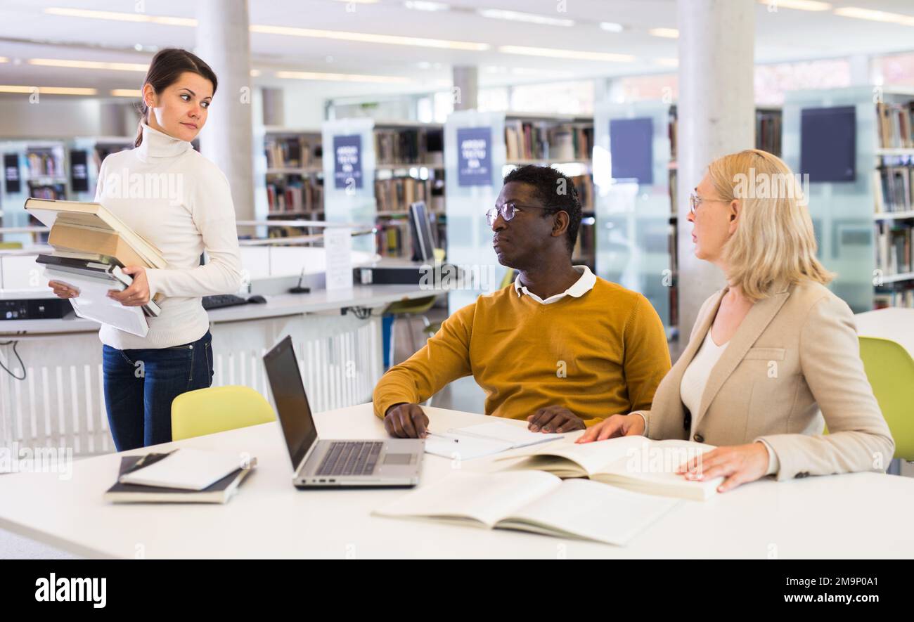 Professor and students communicate in the library Stock Photo - Alamy