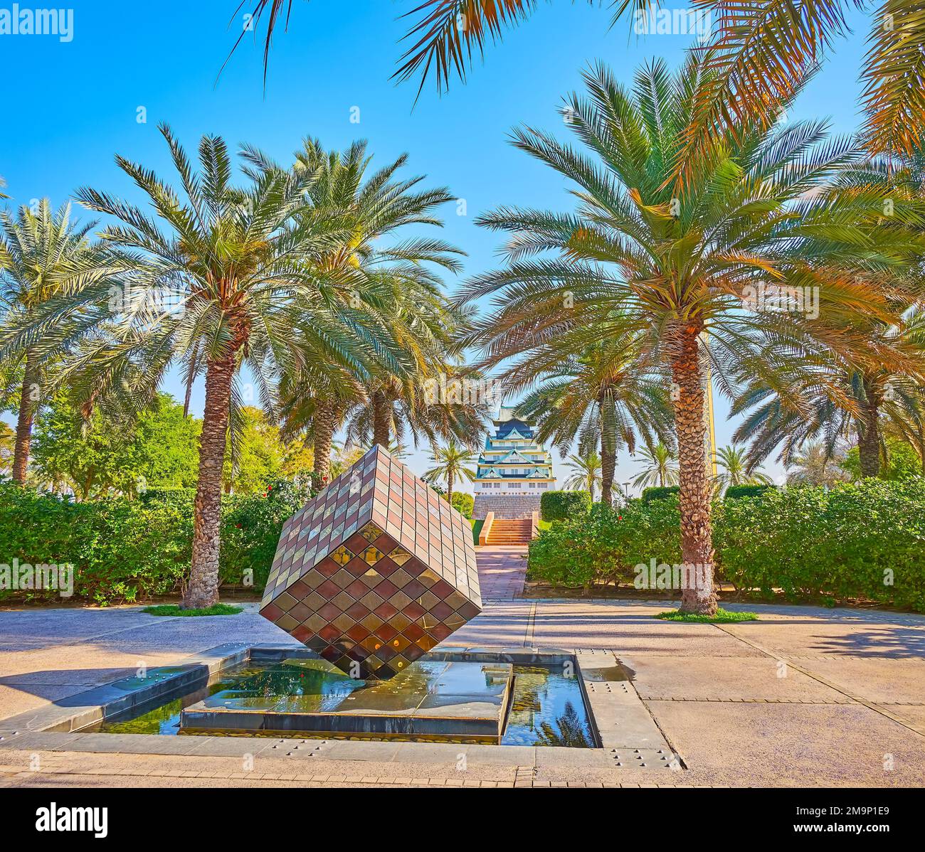 The small fountain with sculpture of balancing cube, surrounded with ...