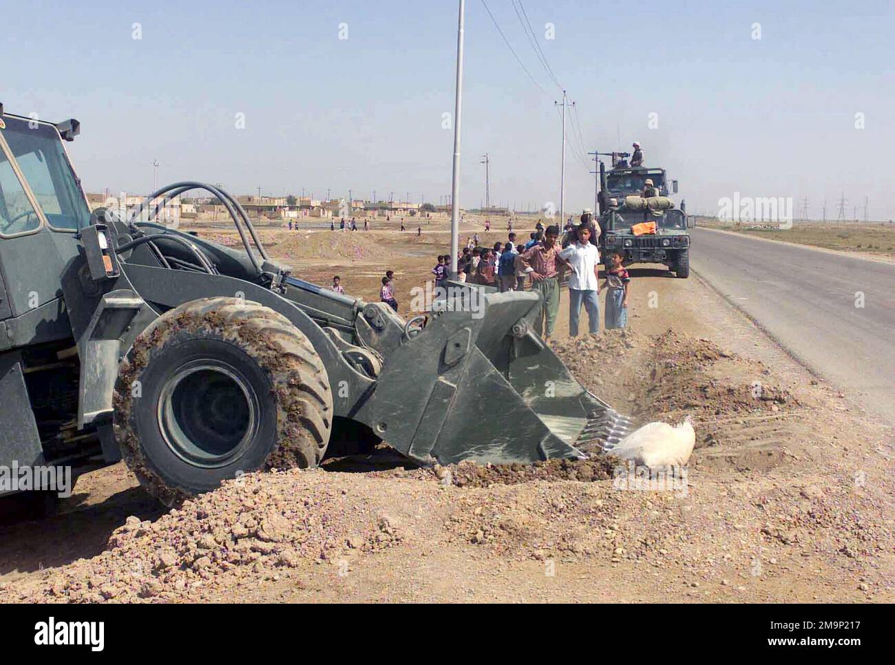 Local Iraqi civilians look on as a US Marine Corps (USMC) Marine ...