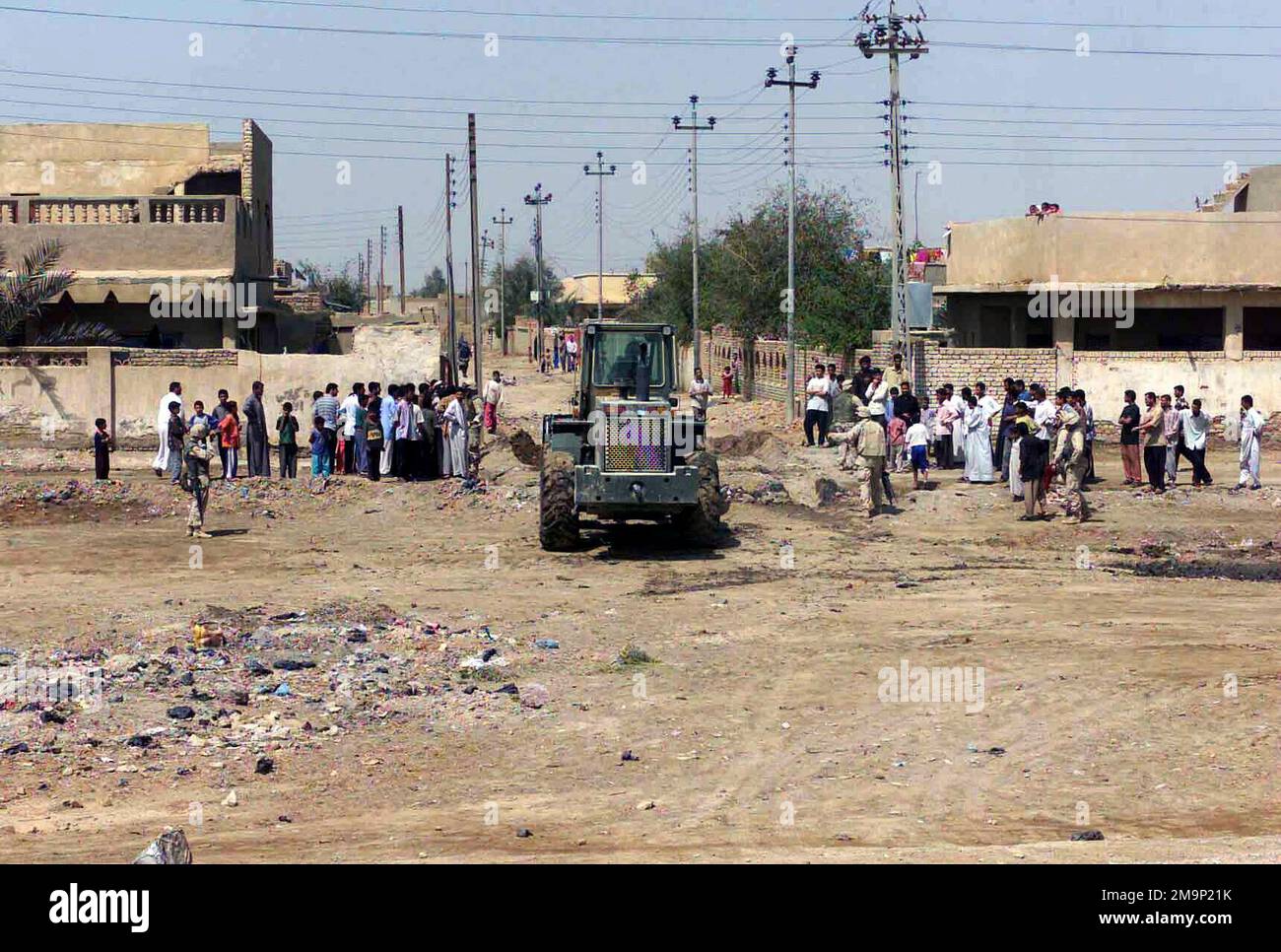 Local Iraqi civilians gather and watch as a US Marine Corps (USMC ...