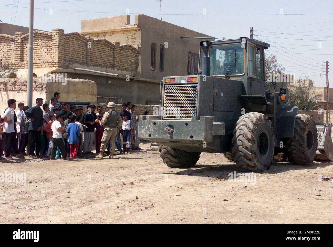 Local Iraqi civilians gather and watch as a US Marine Corps (USMC ...