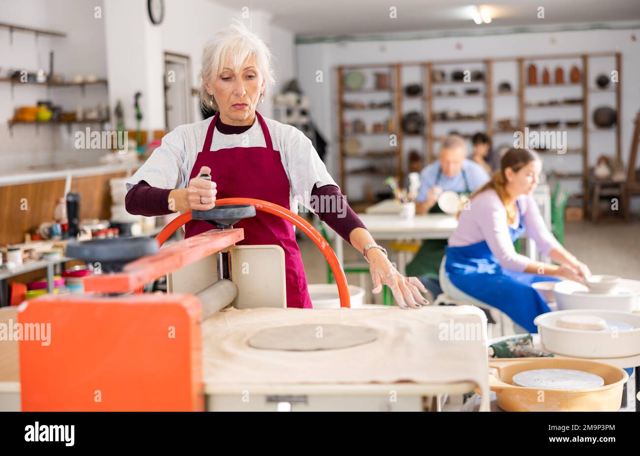 Woman rolling piece of clay on special mechanical machine - craft ...