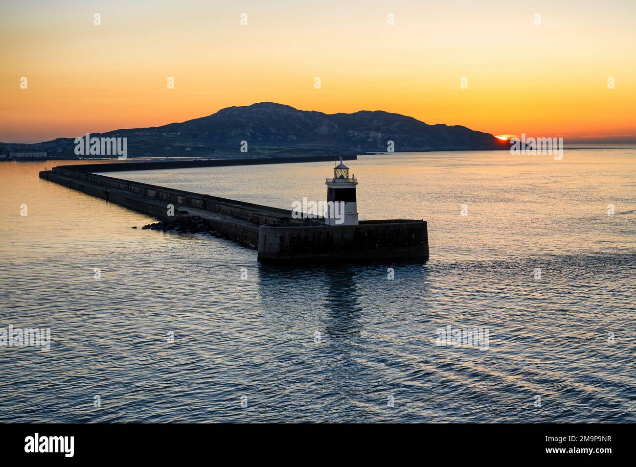 A sunset view of the breakwater and South Stack mountain at Holyhead ...