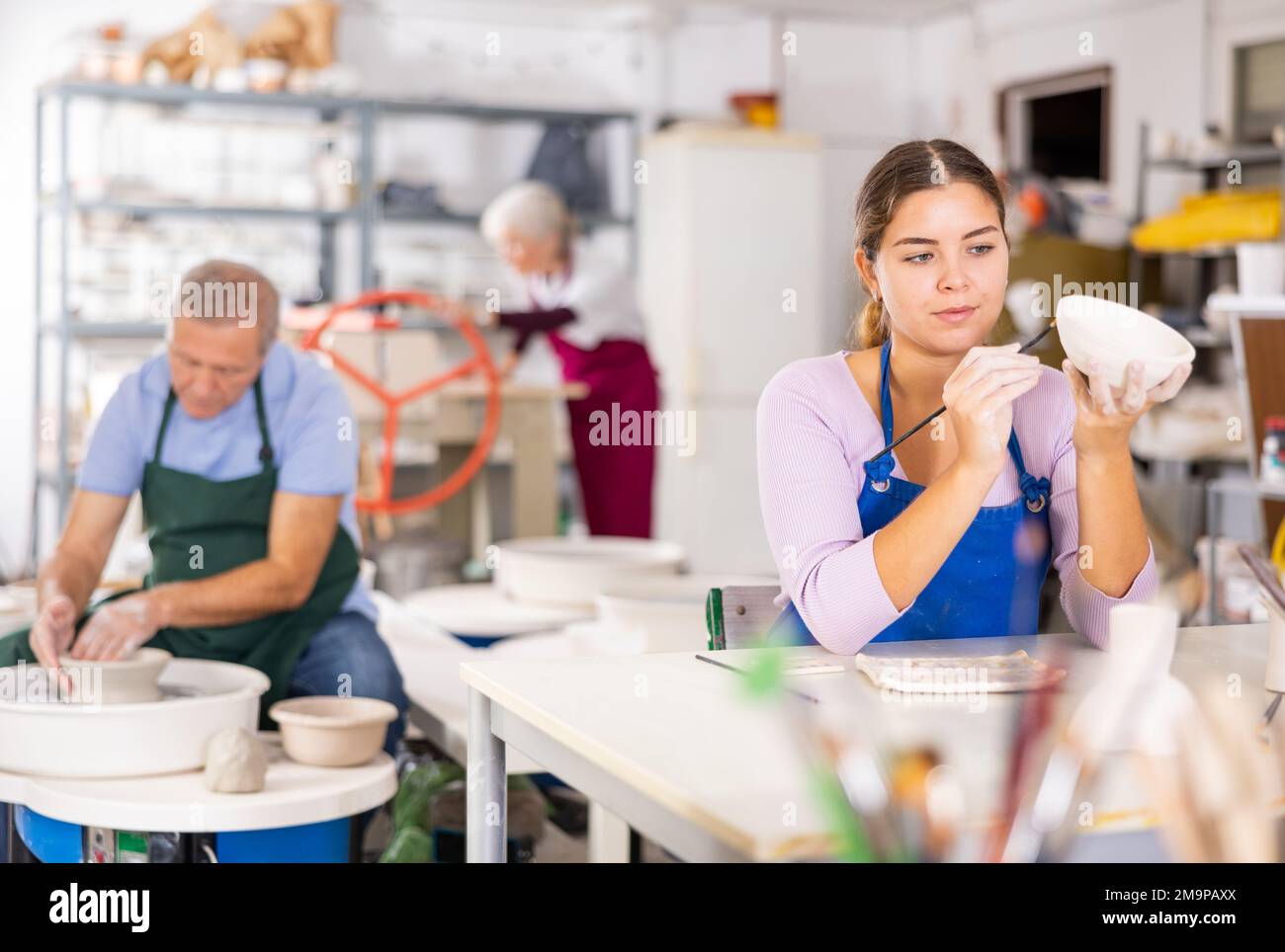 Woman learning to paint pottery at pottery class Stock Photo - Alamy