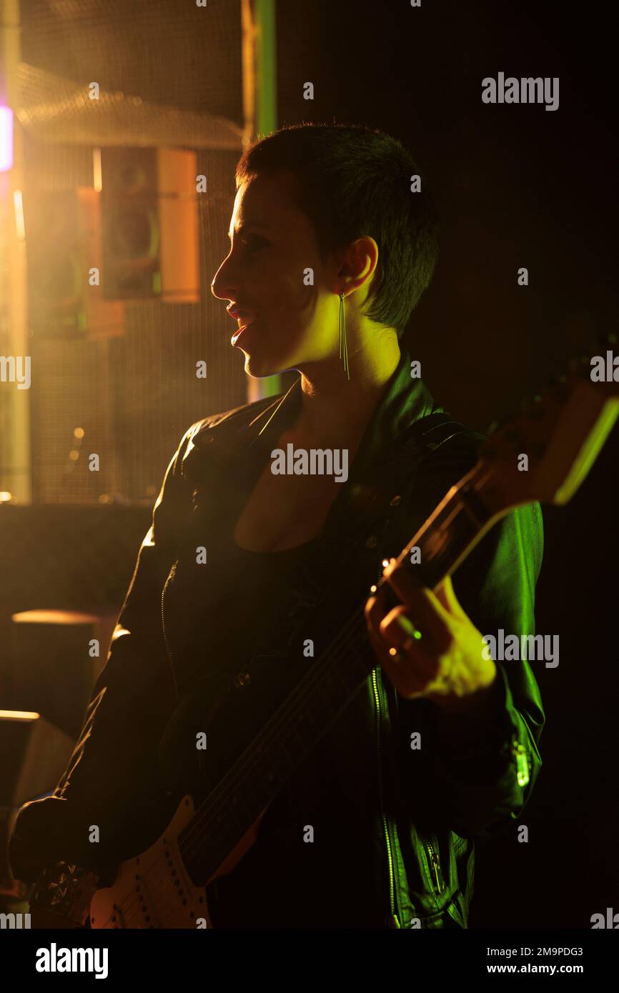 Happy rockstar woman holding electric guitar playing heavy metal song ...