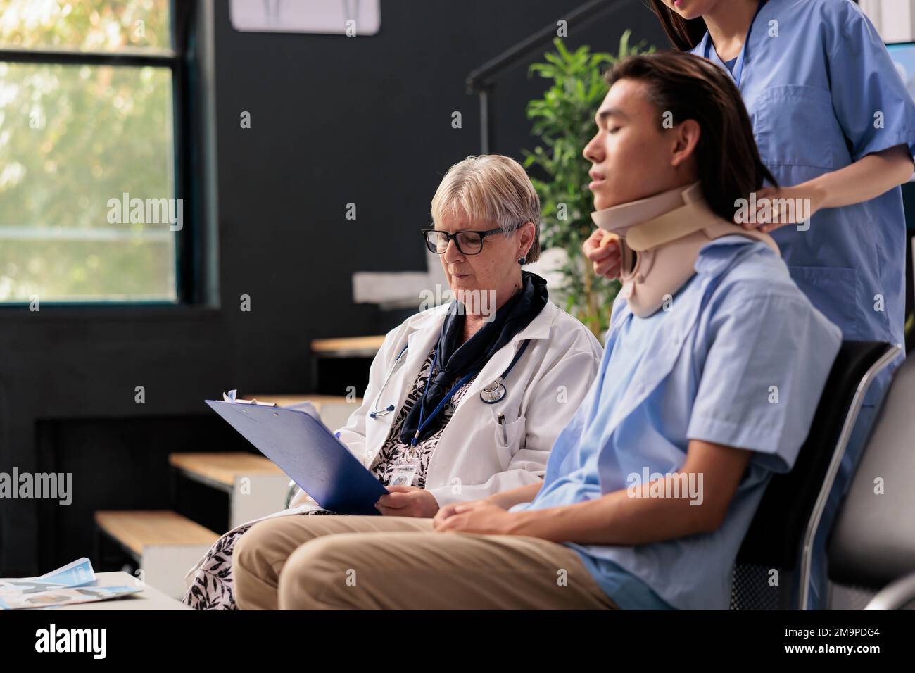 Assistant and physician helping asian patient to take off neck collar ...