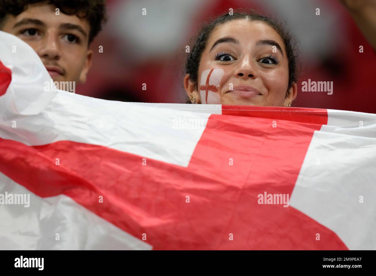 A fan holding an England flag smiles at the camera from the stands ...