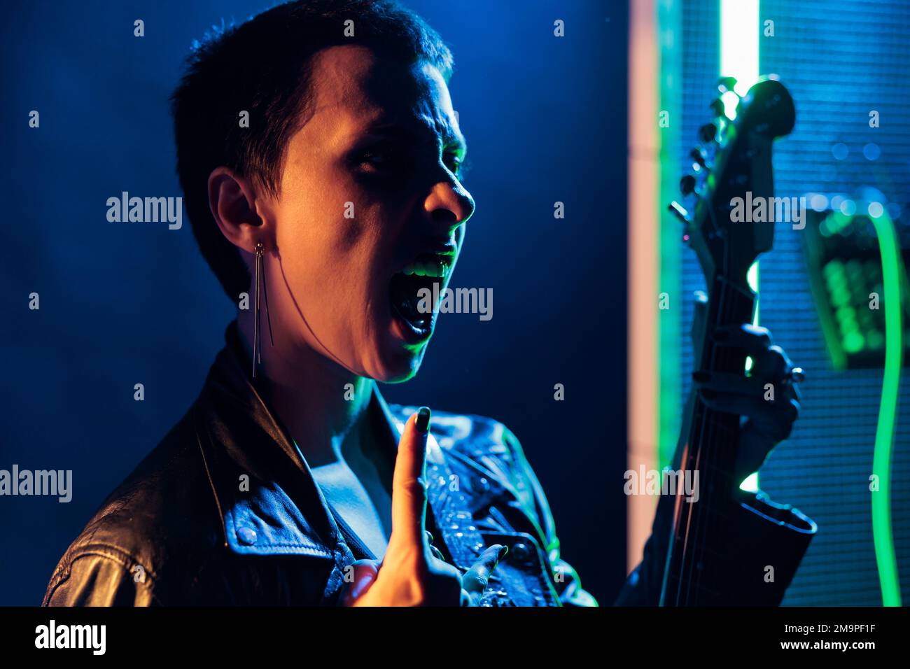 Rockstar woman enjoying to play at electric guitar in studio preparing ...