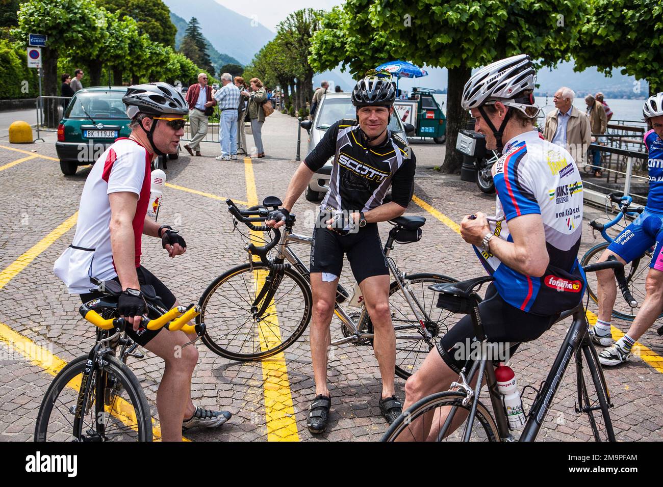 A group of Italian bicycle riders rest up along the shore of Lake Como ...