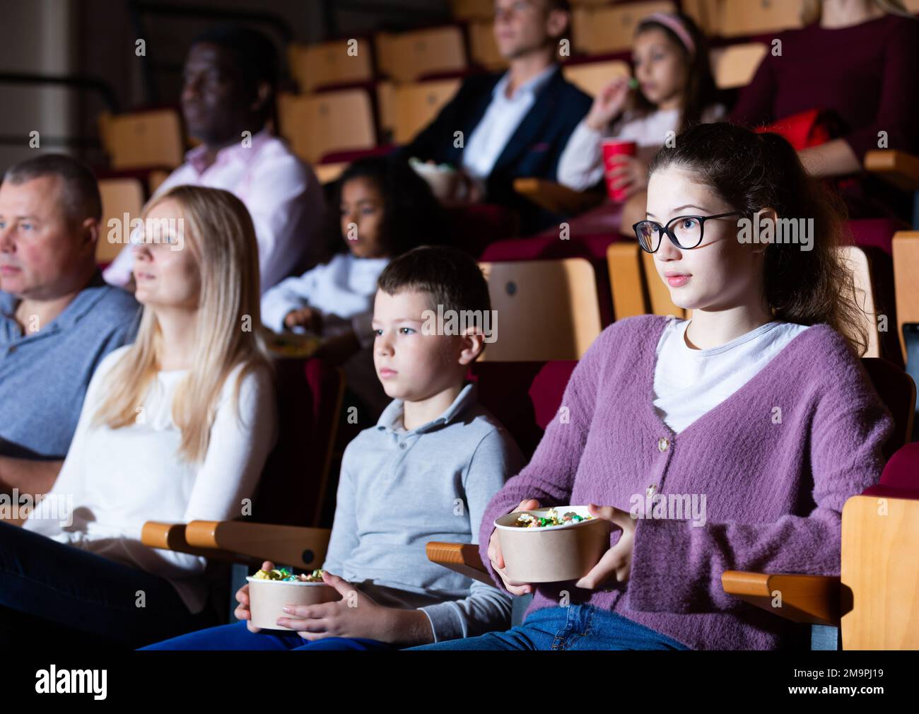 Spectators eating popcorn and watching a movie at cinema Stock Photo ...