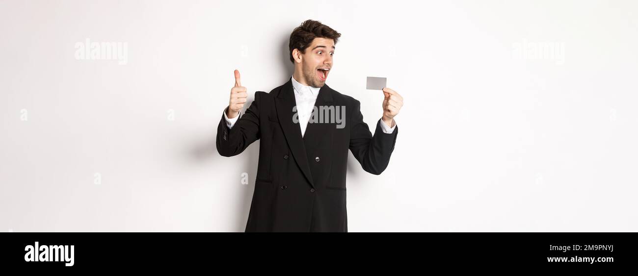Image of excited handsome businessman, showing credit card and thumb-up ...