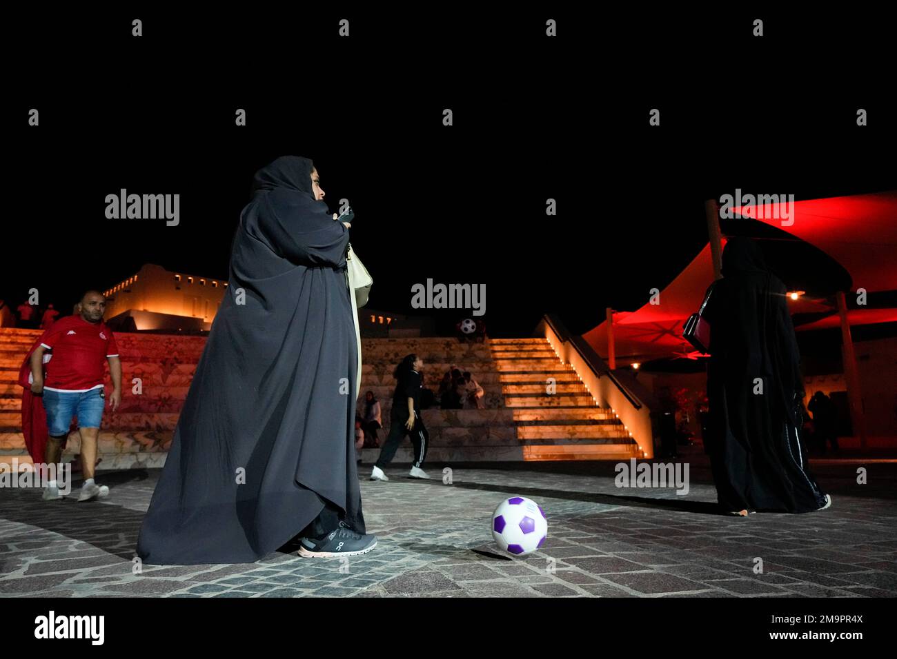 A ball rolls by as women wearing traditional Qatari dresses walk by at ...