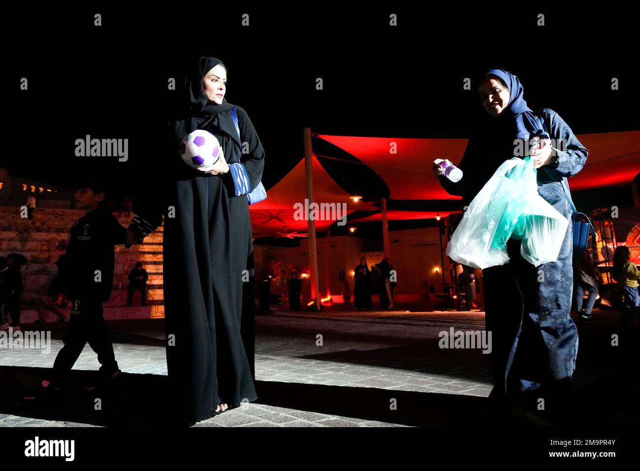 A woman holds a soccer ball while walking at Katara Beach during the ...