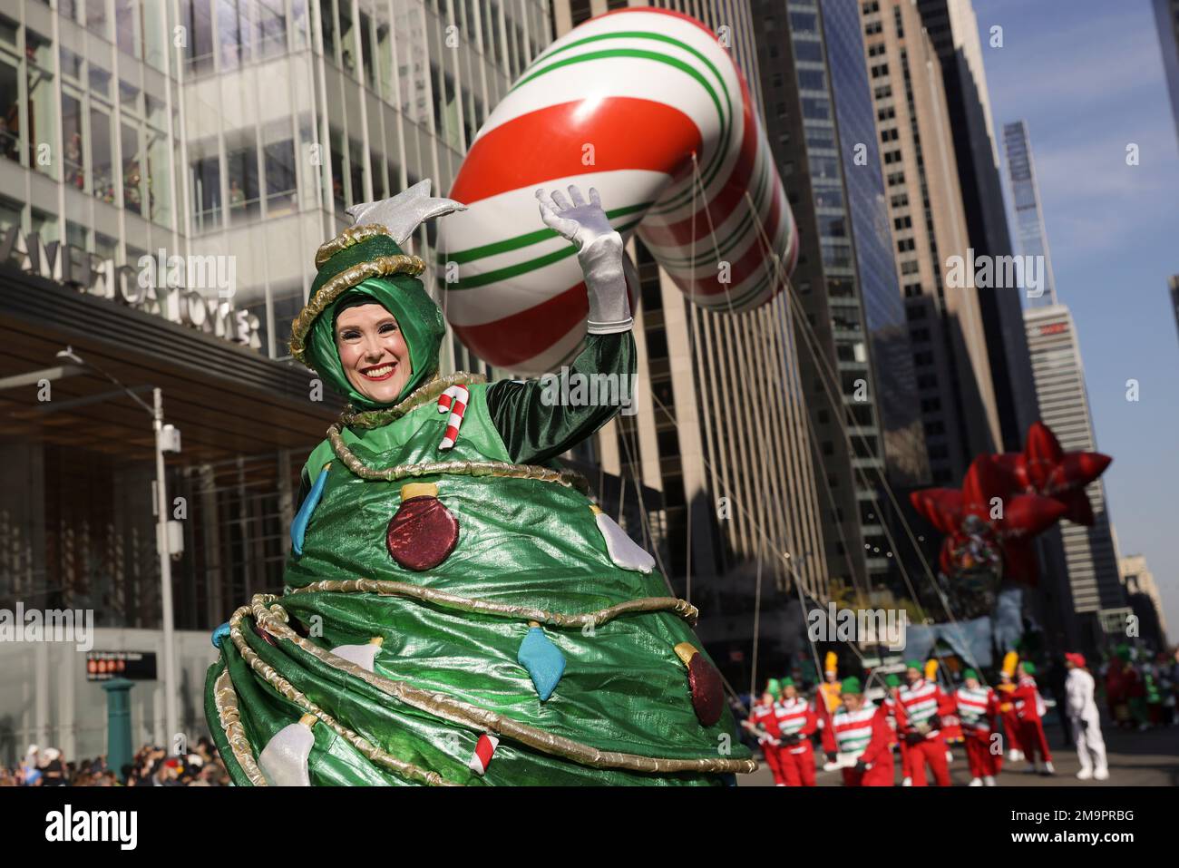 A parade performer in a Christmas Tree costume walks down Sixth Avenue ...
