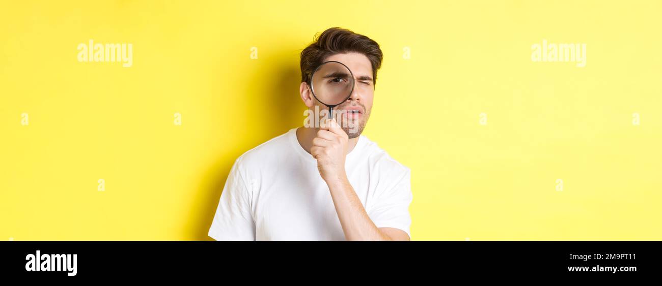 Man looking through magnifying glass with serious and thoughtful look ...