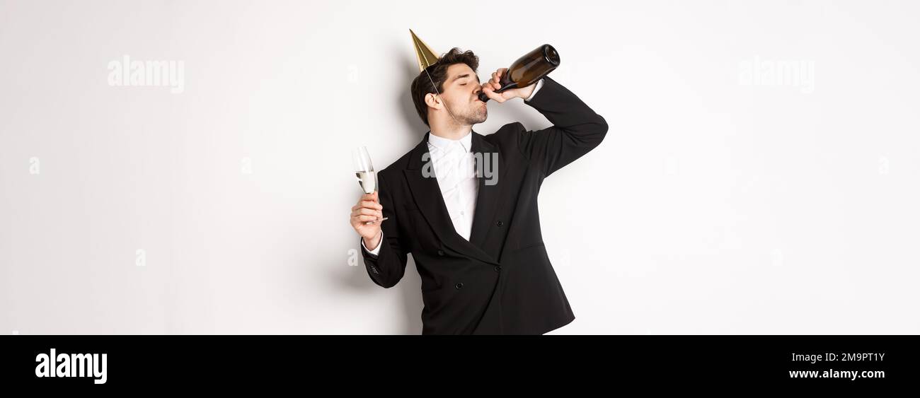 Image of handsome guy in trendy suit, drinking champagne from bottle ...