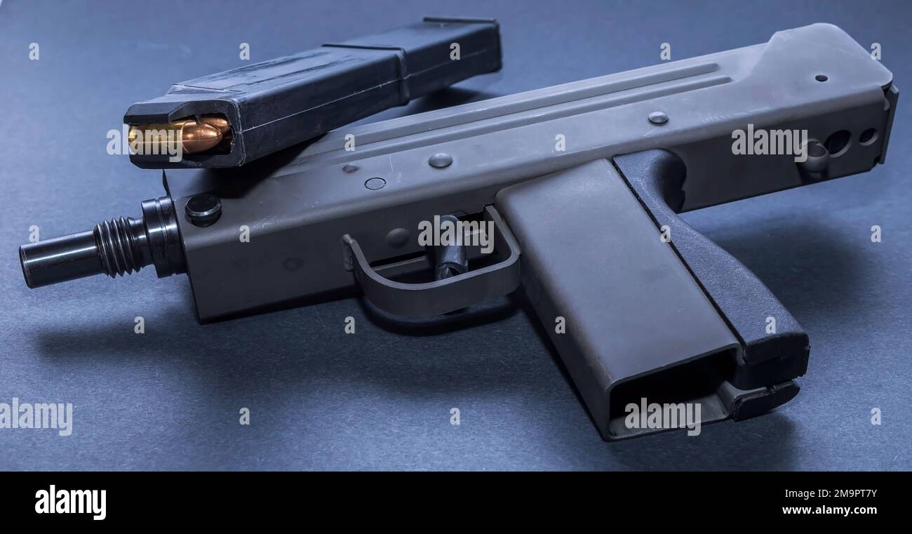 An UZI mini machine gun with a loaded, extended magazine on a black ...