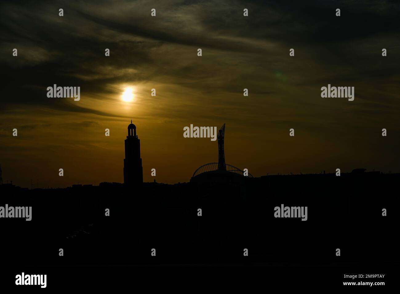 The sun sets behind a mosque and the Khalifa International Stadium ...