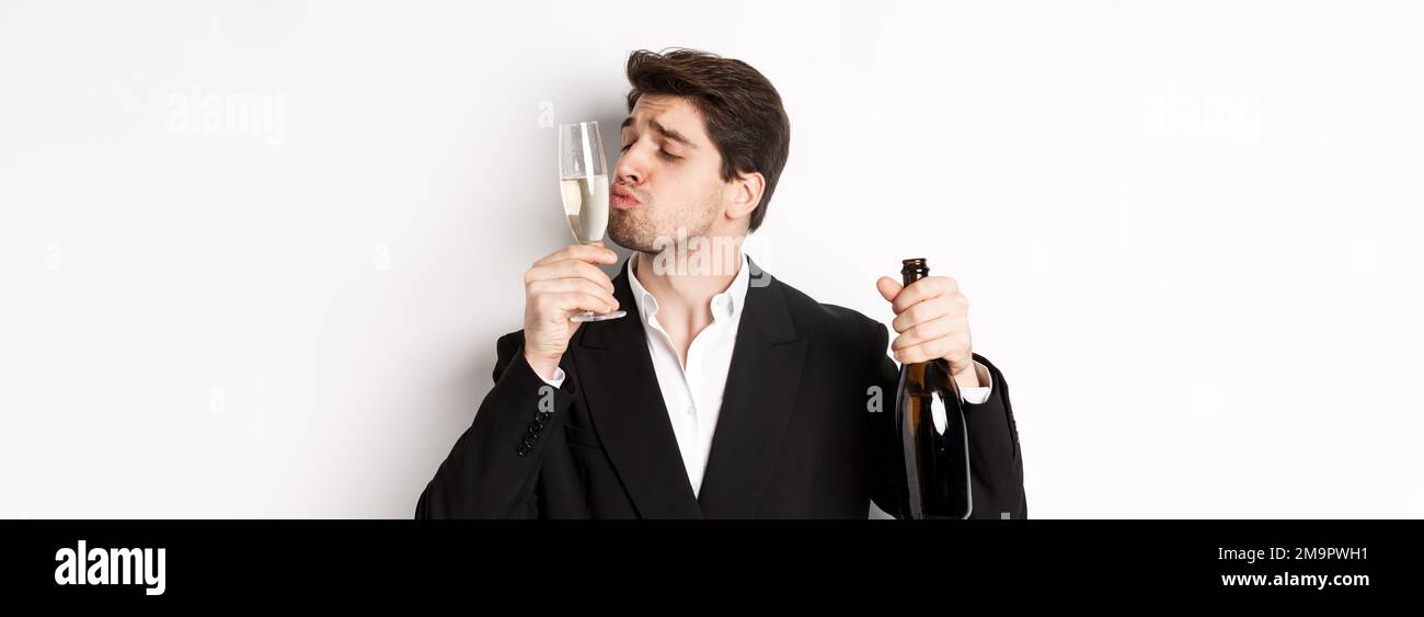 Close-up of handsome man in suit, kissing glass with champagne, getting ...