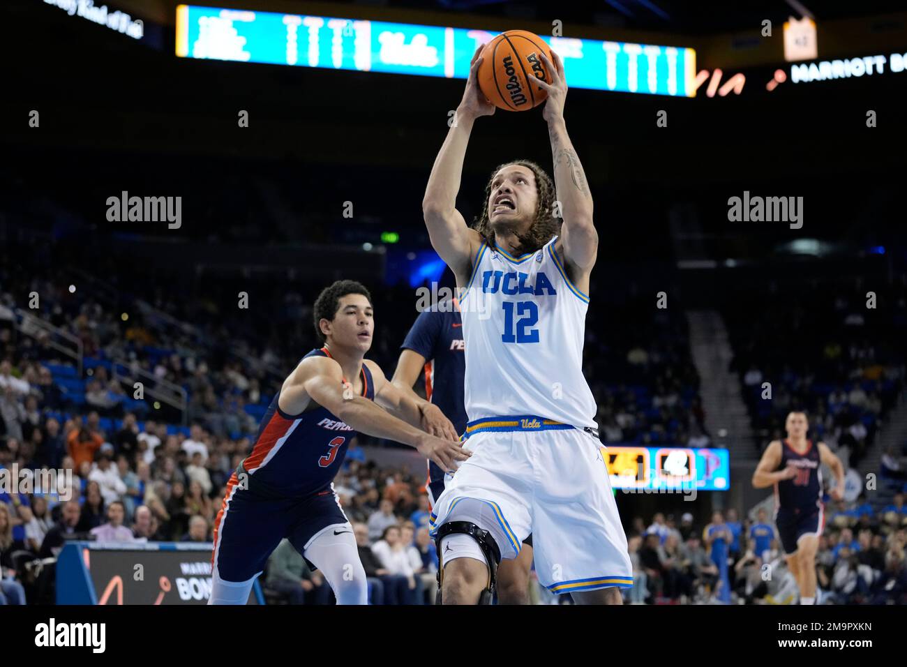 UCLA forward Mac Etienne (12) scores past Pepperdine guard Malik Moore ...