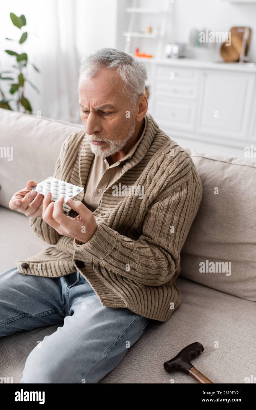 senior man with parkinson disease sitting on couch in knitted cardigan ...