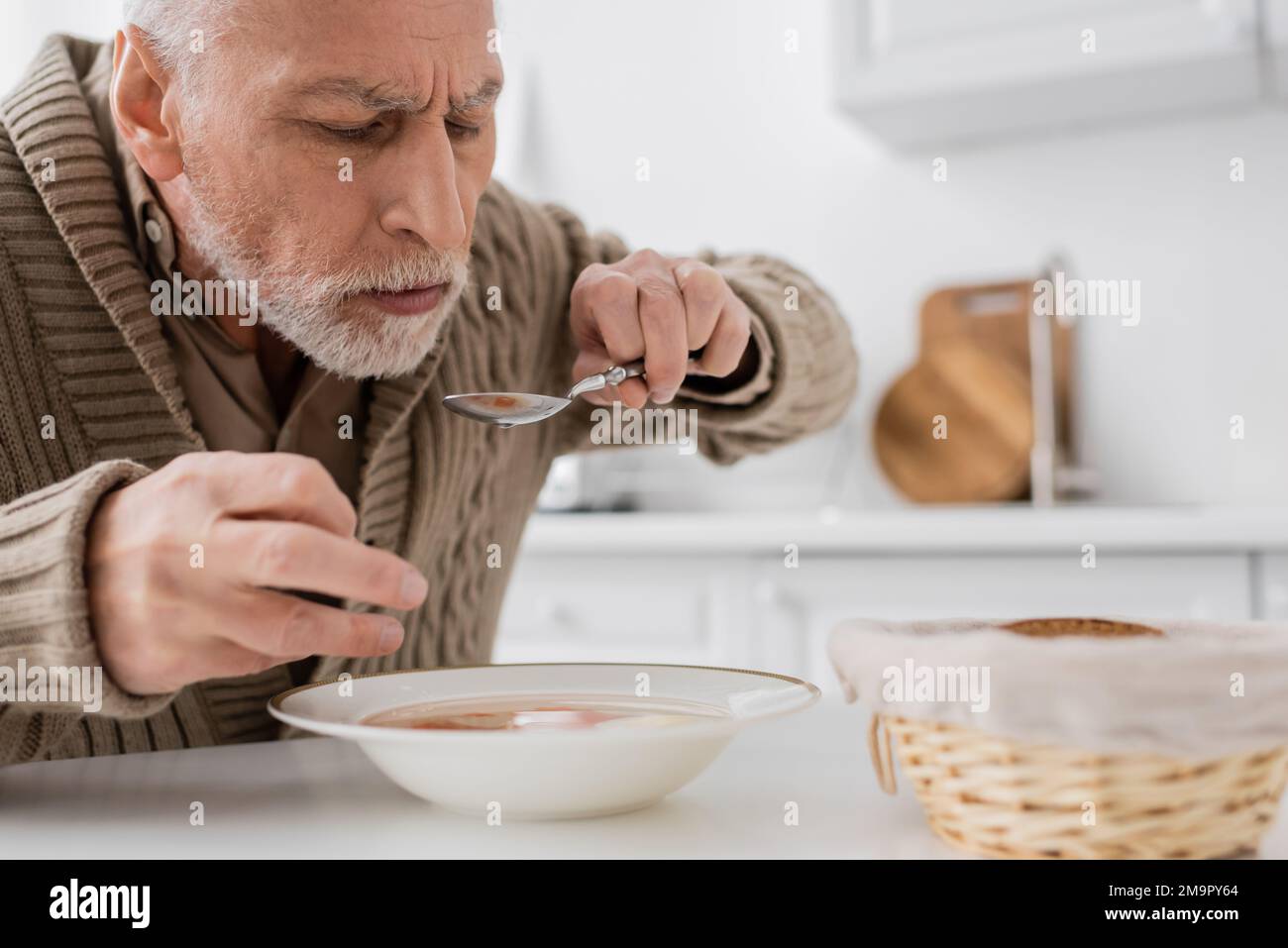aged man with parkinson disease holding spoon in trembling hand while ...