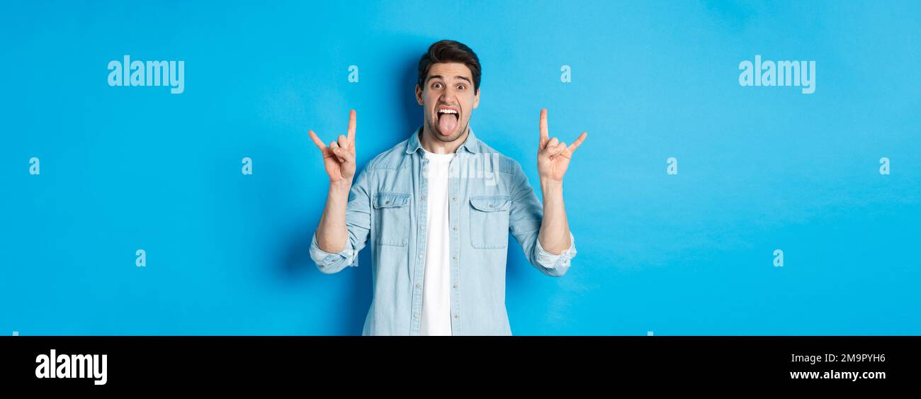 Cool guy having fun, enjoying concert, showing rock sign and tongue ...
