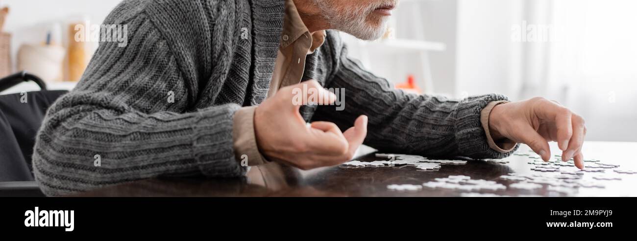 partial view of man suffering from parkinson disease combining jigsaw ...