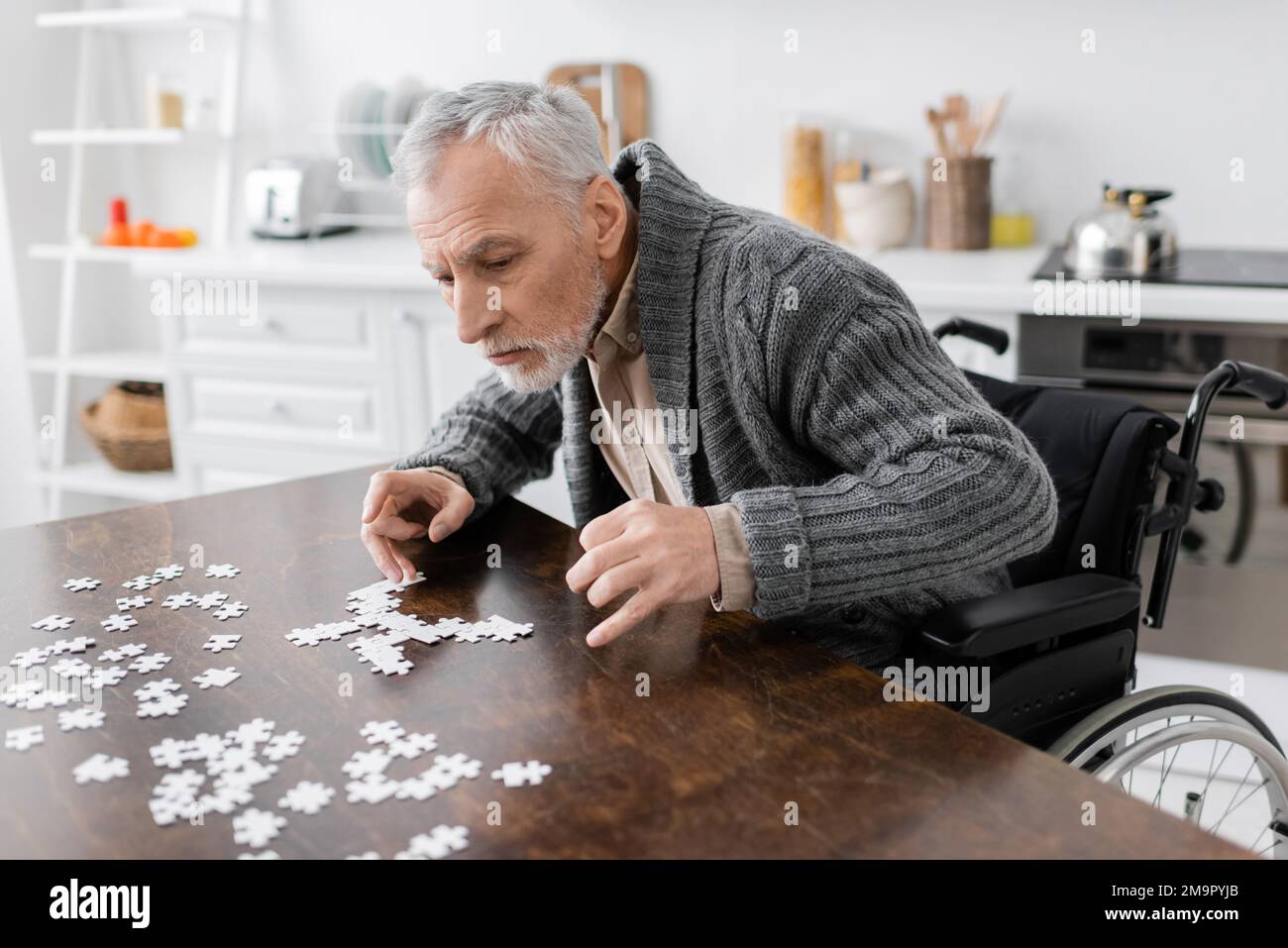 man with disability and parkinson syndrome sitting near jigsaw puzzle ...