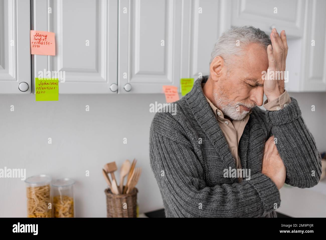 depressed man with alzheimer disease touching forehead while standing ...