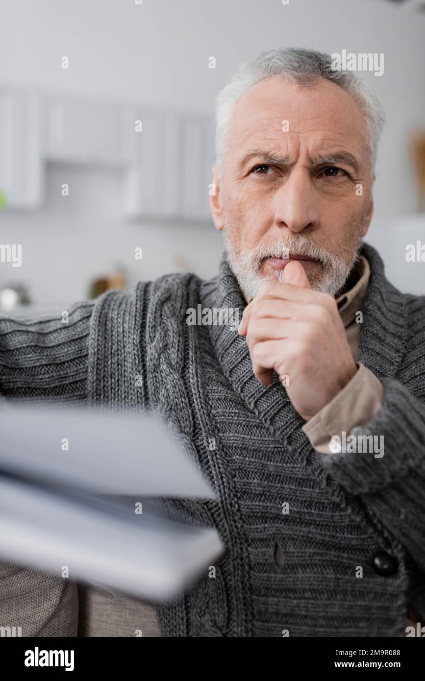 aged man with alzheimer disease looking away and thinking near blurred ...