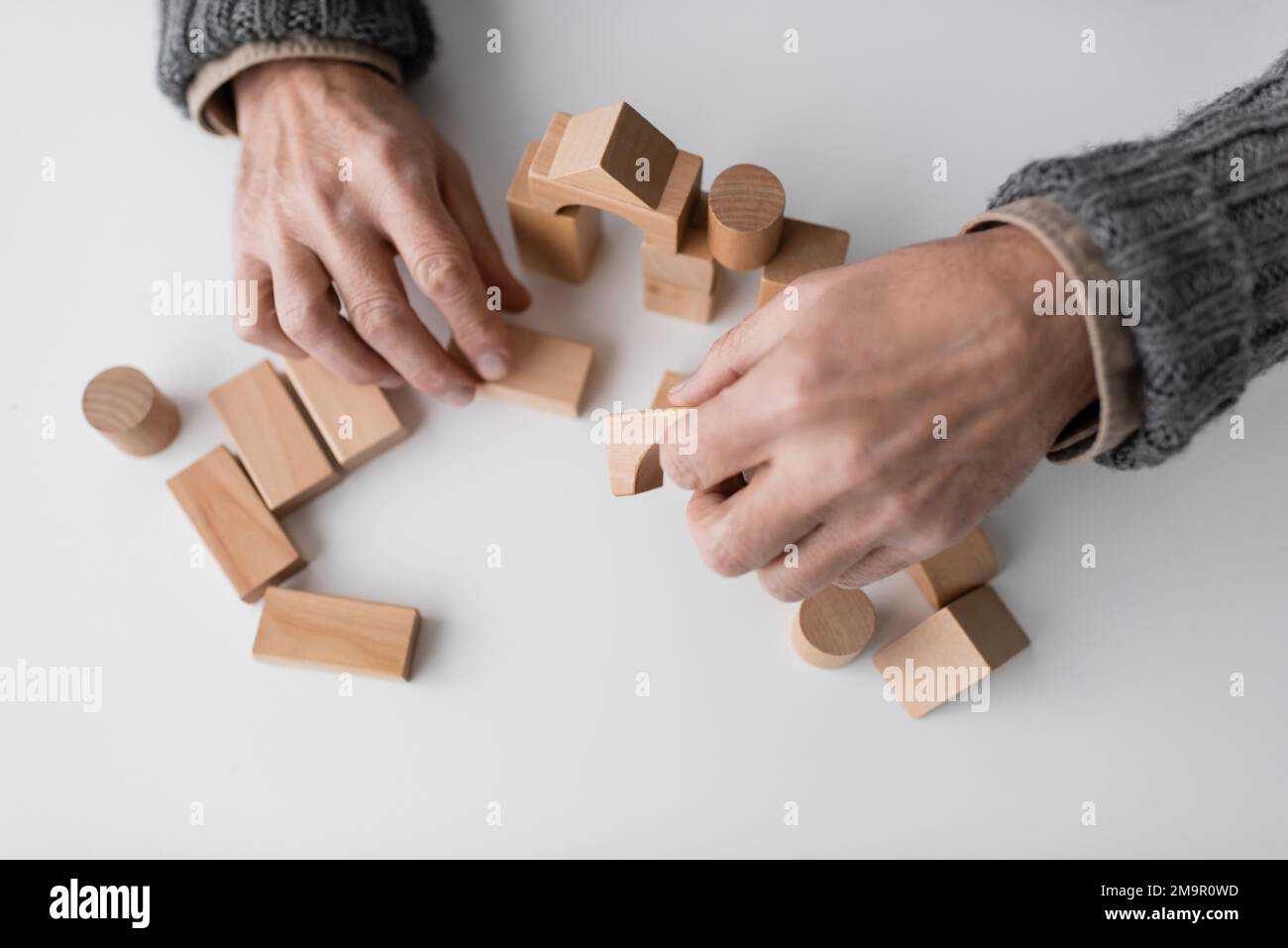 top view of cropped man with alzheimer syndrome playing with wooden ...