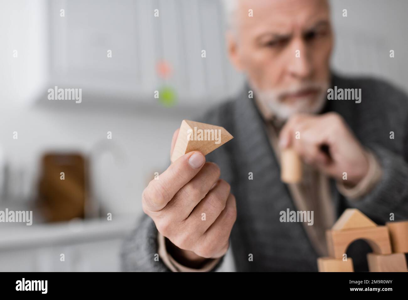 selective focus of wooden block in hand of senior man with alzheimer ...