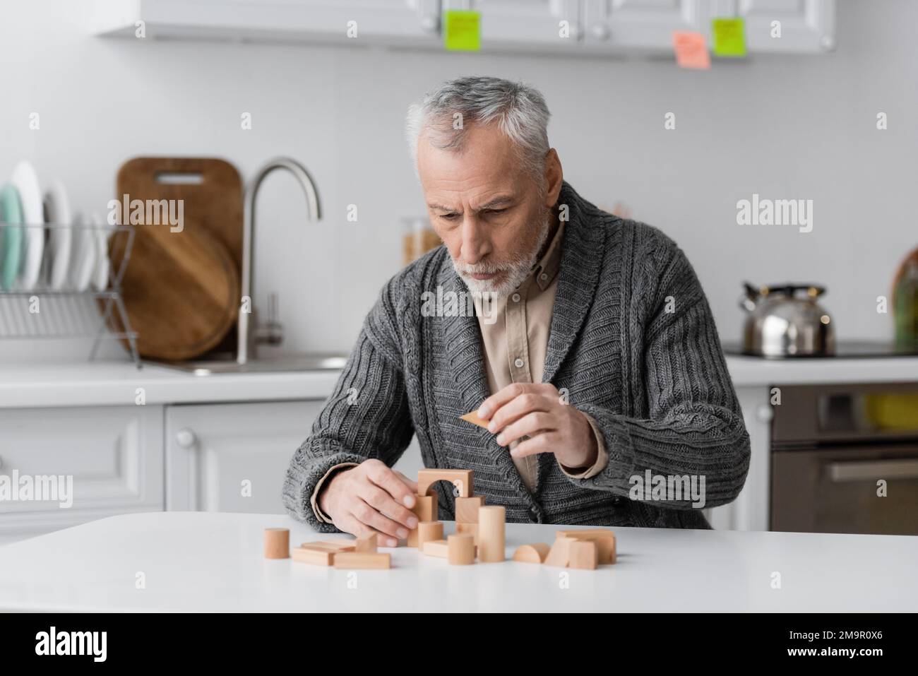 senior man with alzheimer syndrome playing buildings blocks game at ...