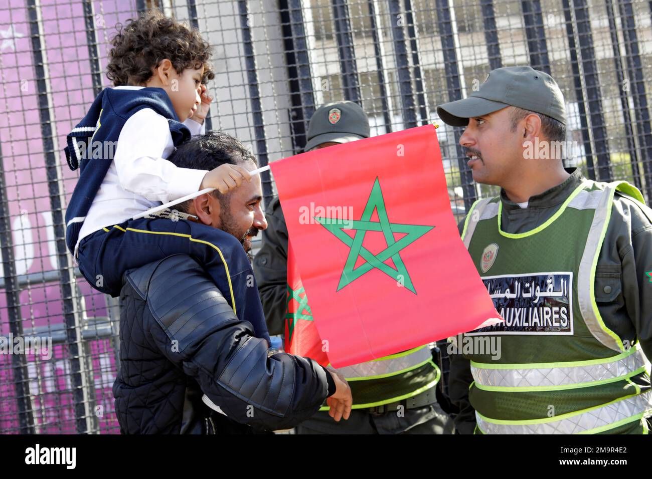 A man carries his son past Auxiliary Force officers as Moroccan soccer ...