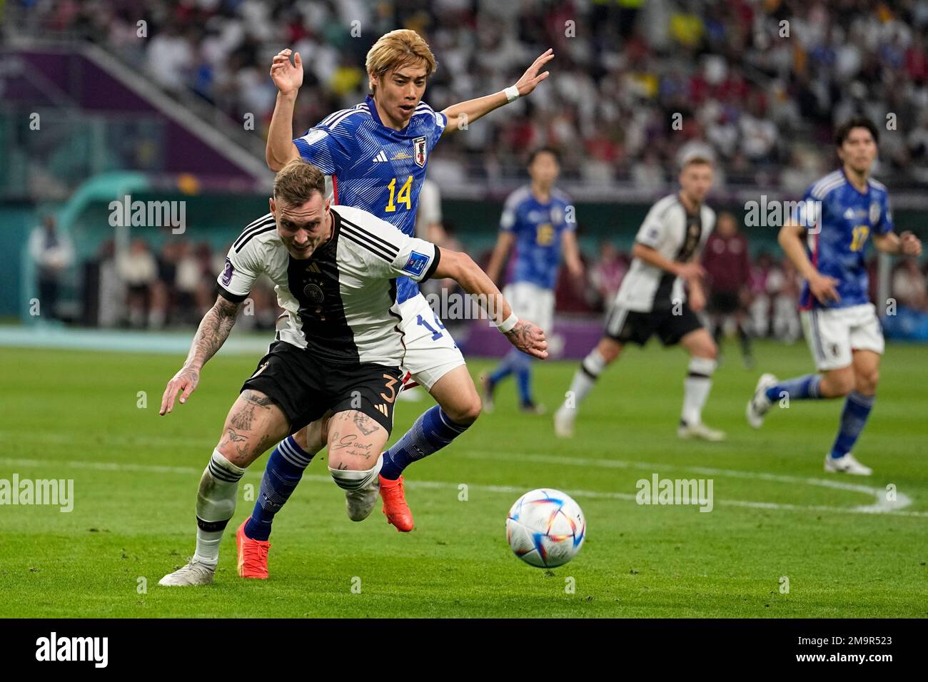 Japan's Junya Ito, center, and Germany's David Raum battle for the ball ...