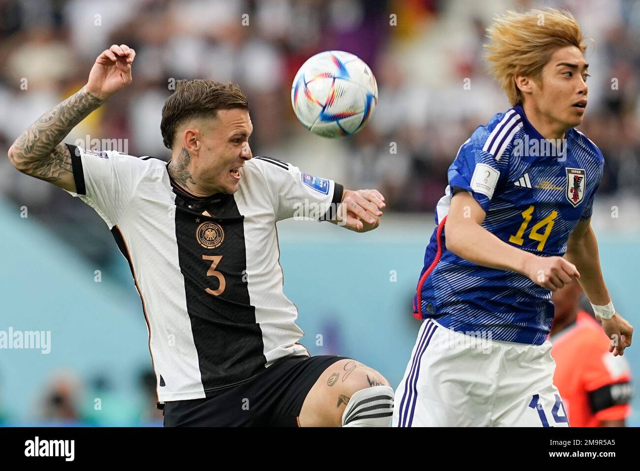 Germany's David Raum, left, and Japan's Junya Ito fight for the ball ...